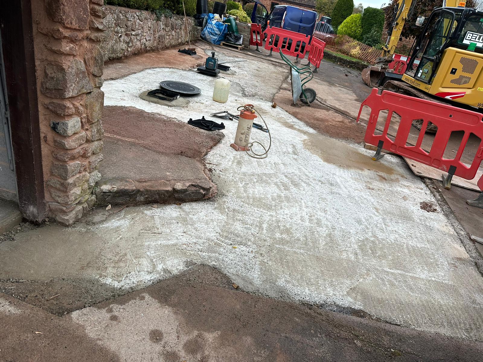 Installation of a new sewage treatment plant under a tarmacked driveway ...